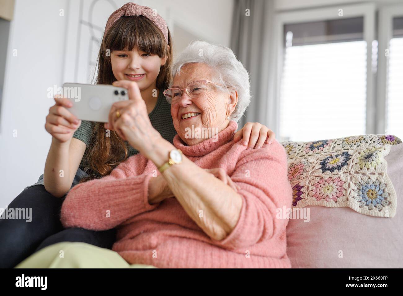 Grandmother with cute girl scrolling on smartphone, girl teaching ...