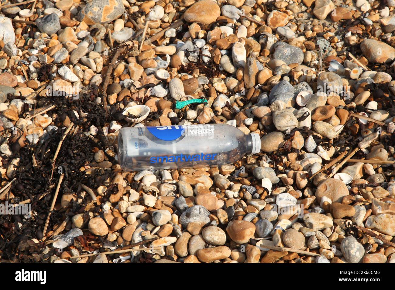 Discarded plastic bottle branded Smart Water on pebble beach in ...