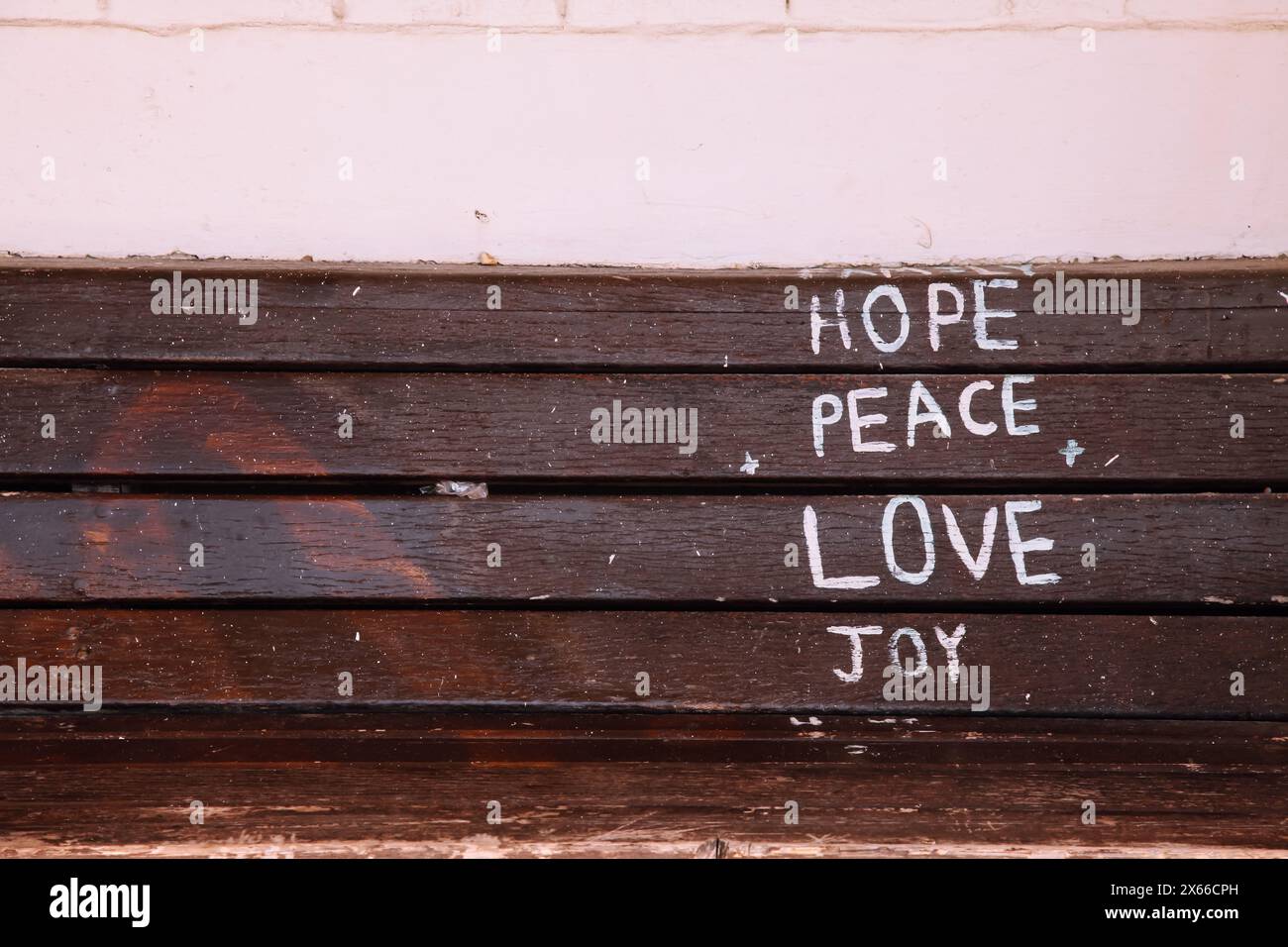 The words Hope Peace Love Joy painting graffiti on wooden bench along ...