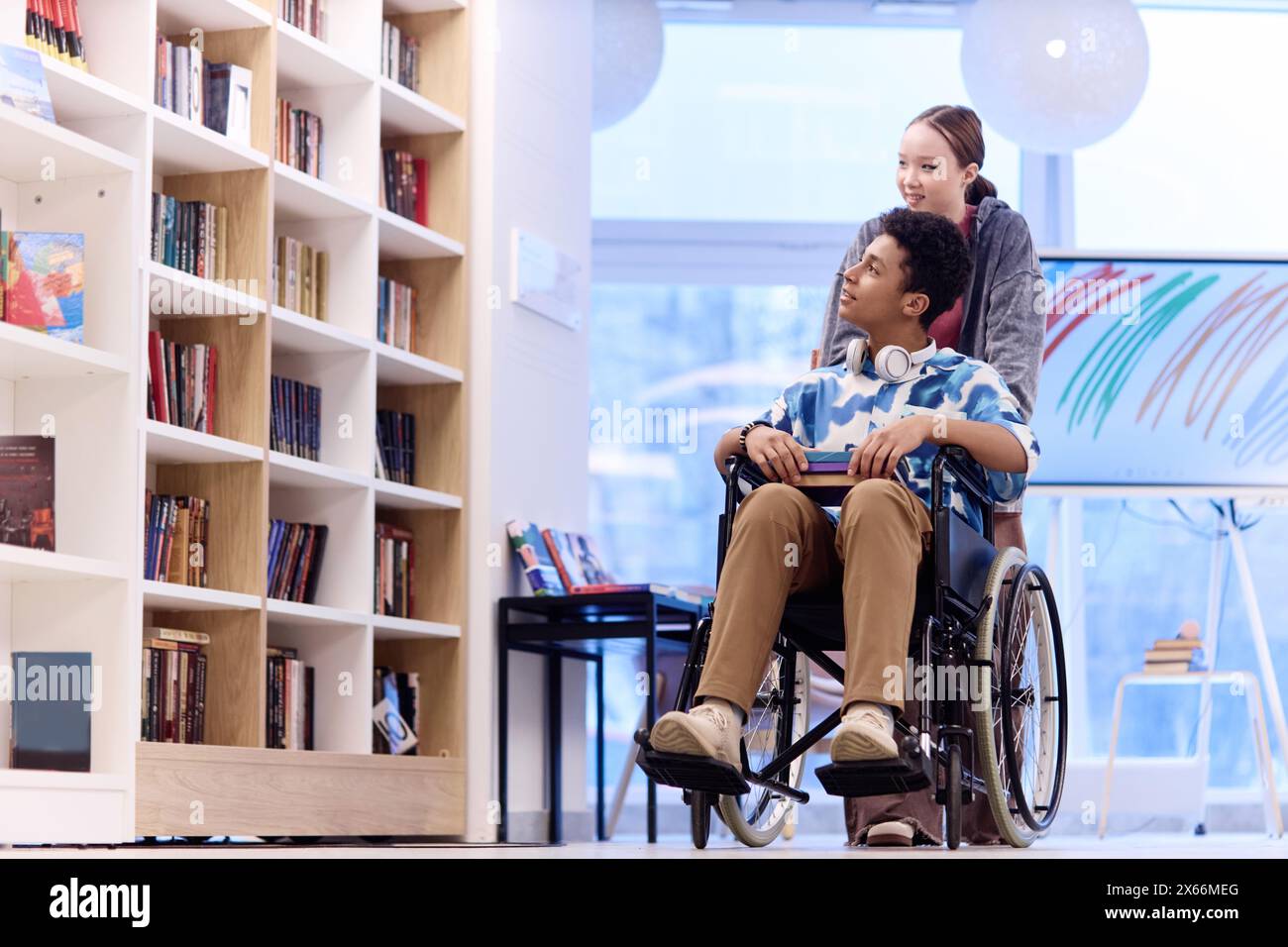 Full length portrait of teenage boy with disability choosing books in ...
