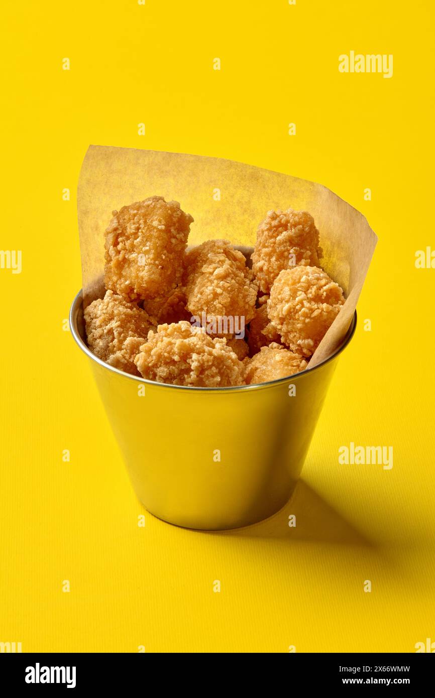Metal bucket with chicken nuggets on yellow background Stock Photo - Alamy