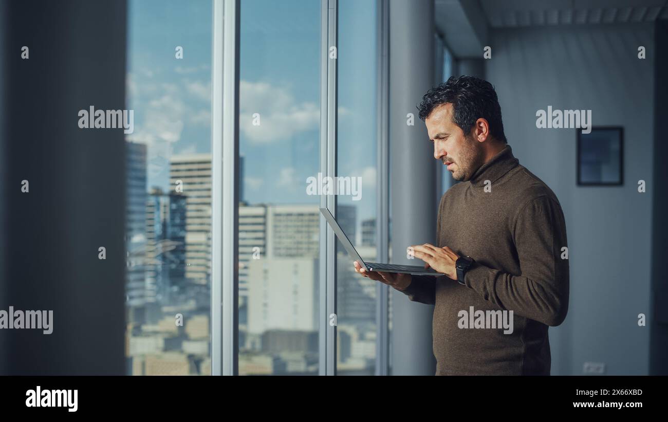 Thoughtful Middle Eastern Businessman Using Laptop while Standing in ...