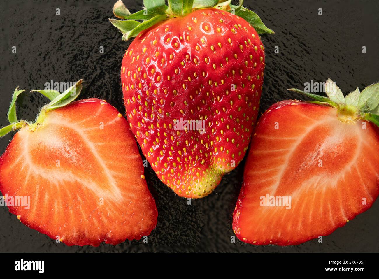 Close up of a strawberry and two half strawberries left and right on a ...