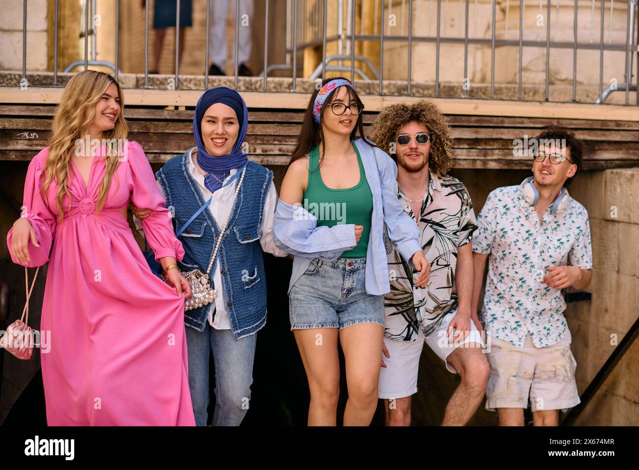 A diverse group of tourists, dressed in summer attire, strolls through ...