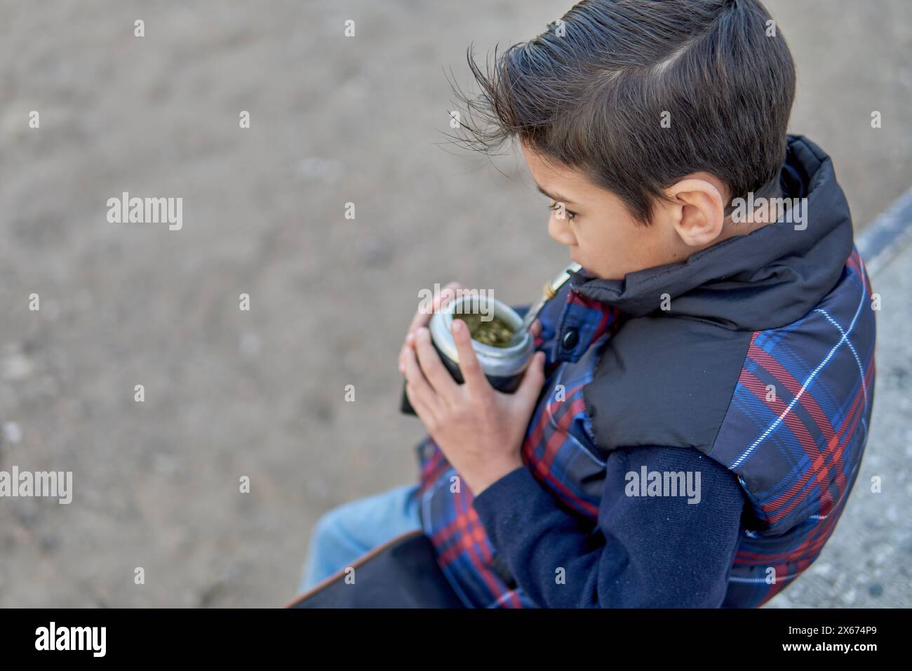 portrait of latin argentinian boy sitting outside drinking mate, close ...