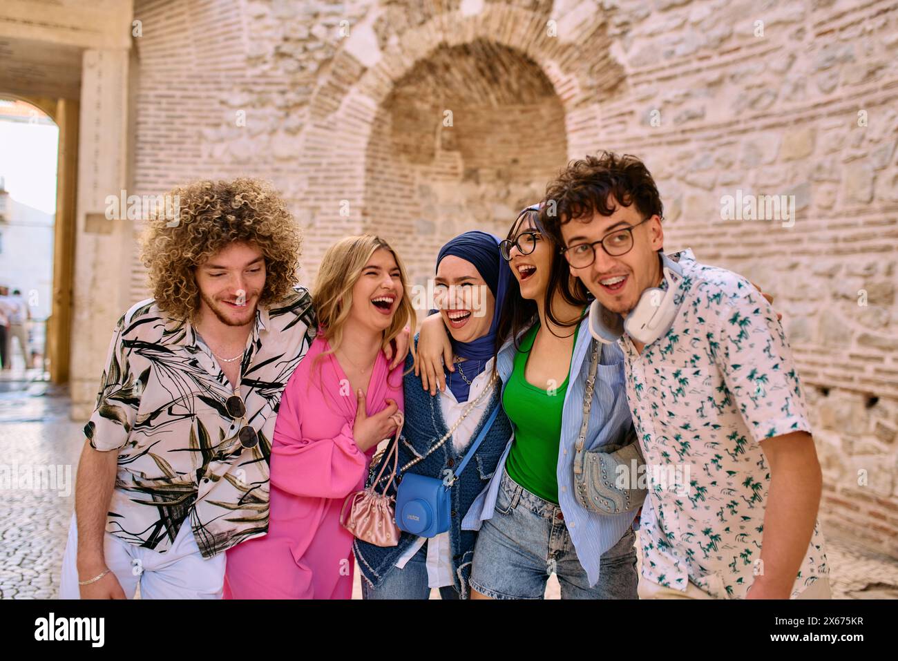 A diverse group of tourists, dressed in summer attire, strolls through ...