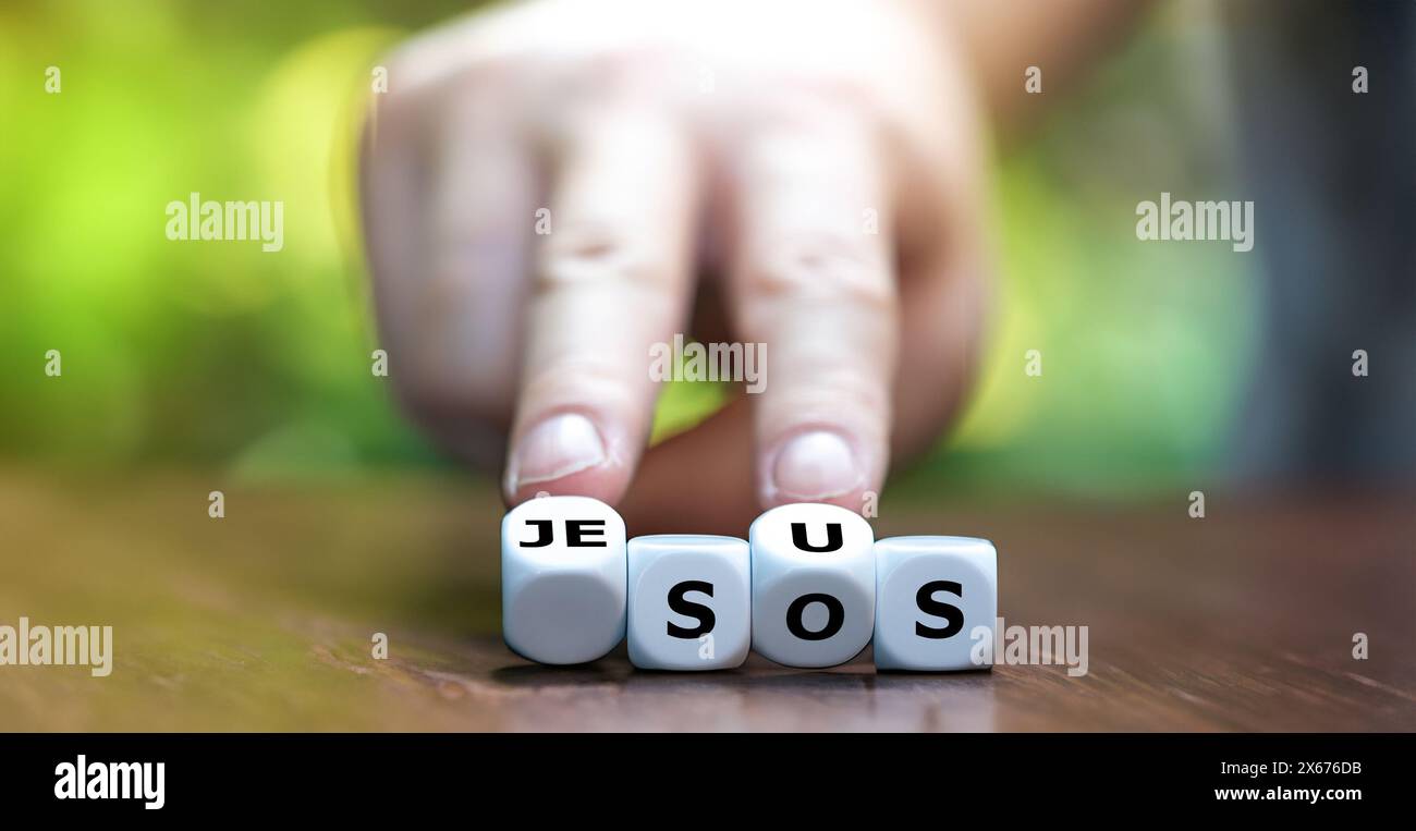 Hand turns dice and changes the expression 'SOS' to 'Jesus'. Symbol ...