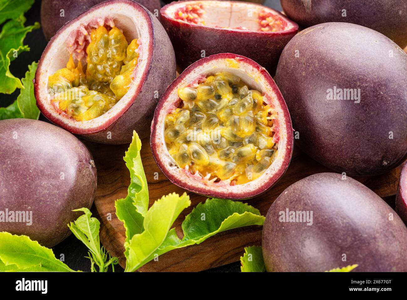 Ripe passion fruits with passion fruit seeds and passionfruit leaves on a gray stone table. Nice ...