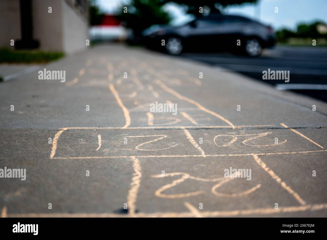 Selective focus on chalk numbers with a girl playing hop-scotch ...