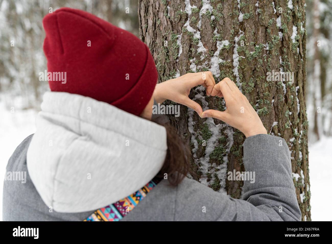 Woman expressing love for nature by making heart shape with hands in ...