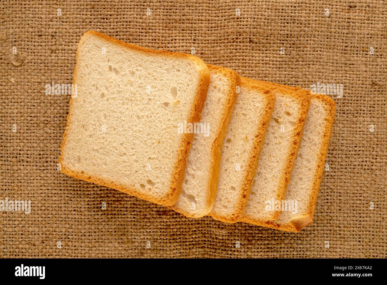 Several pieces of white toaster bread on a jute cloth, macro, top view ...