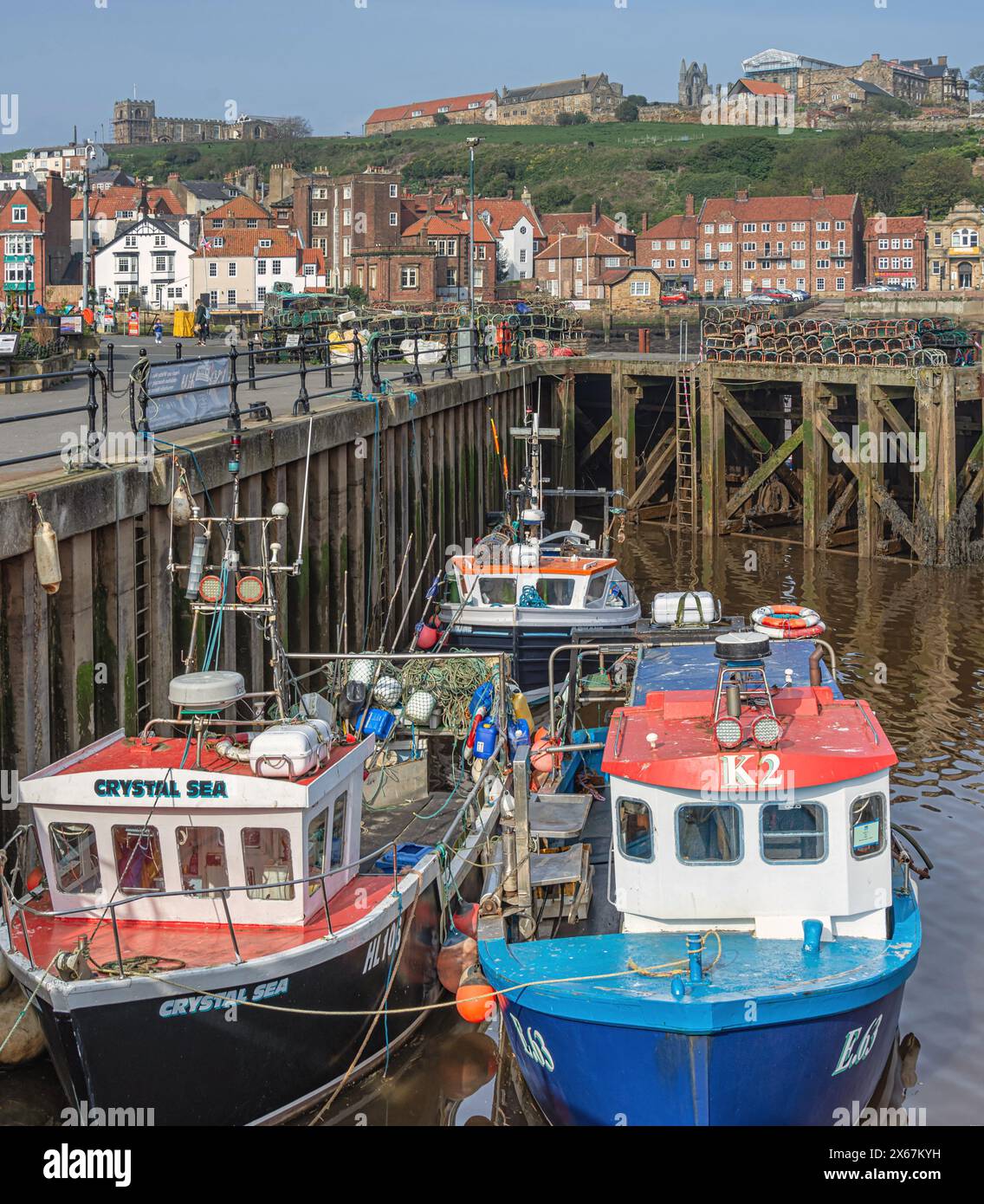 Small fishing boats in Whitby harbour reflected in the water. The decks ...