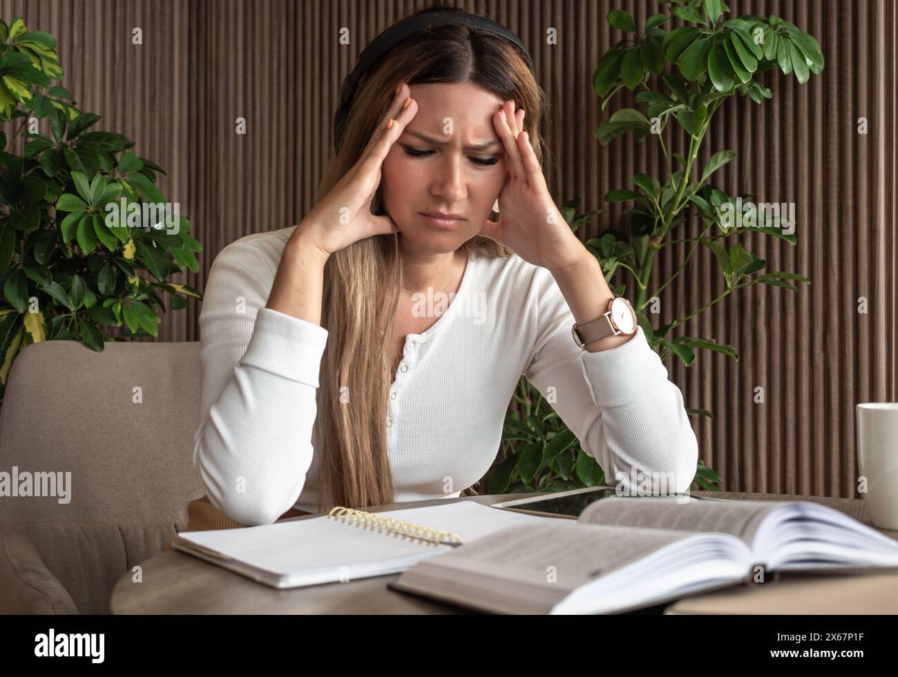 Focused yet stressed adult woman studying at home, showing signs of ...