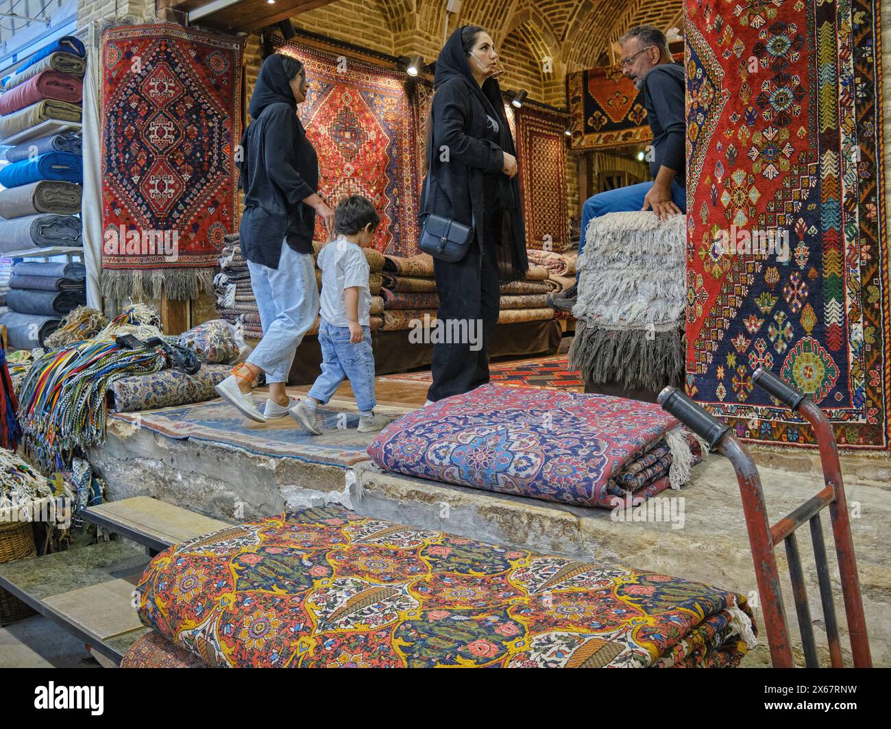 Young Iranian woman with child walk into a carpet shop in the Vakil ...
