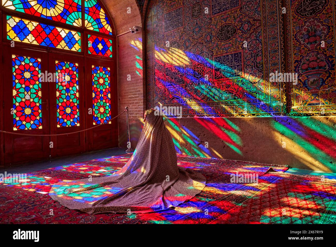 A woman sits in the light from multi-colored stained-glass windows ...