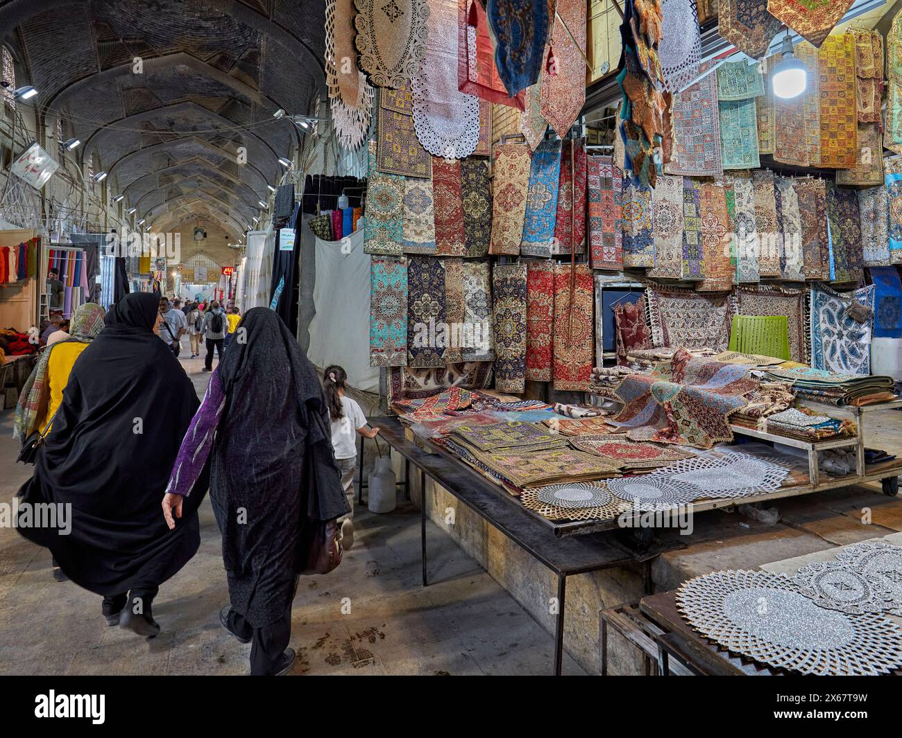 Women wearing chadors walk by a handicraft shop selling Termeh ...