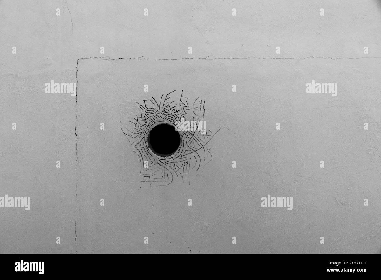 closeup of a round hole on white wall with green color linear pattern ...