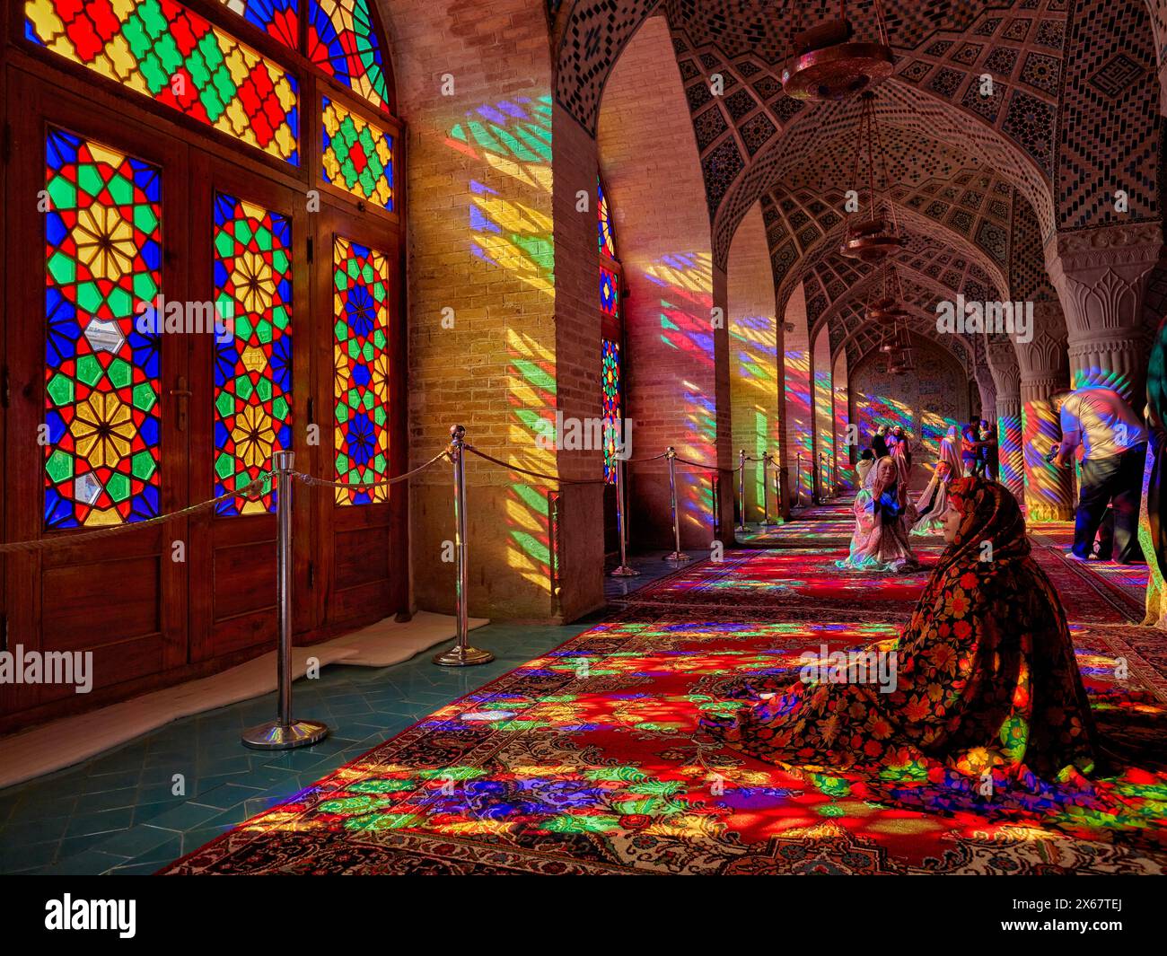 A woman sits in the light from multi-colored stained-glass windows ...
