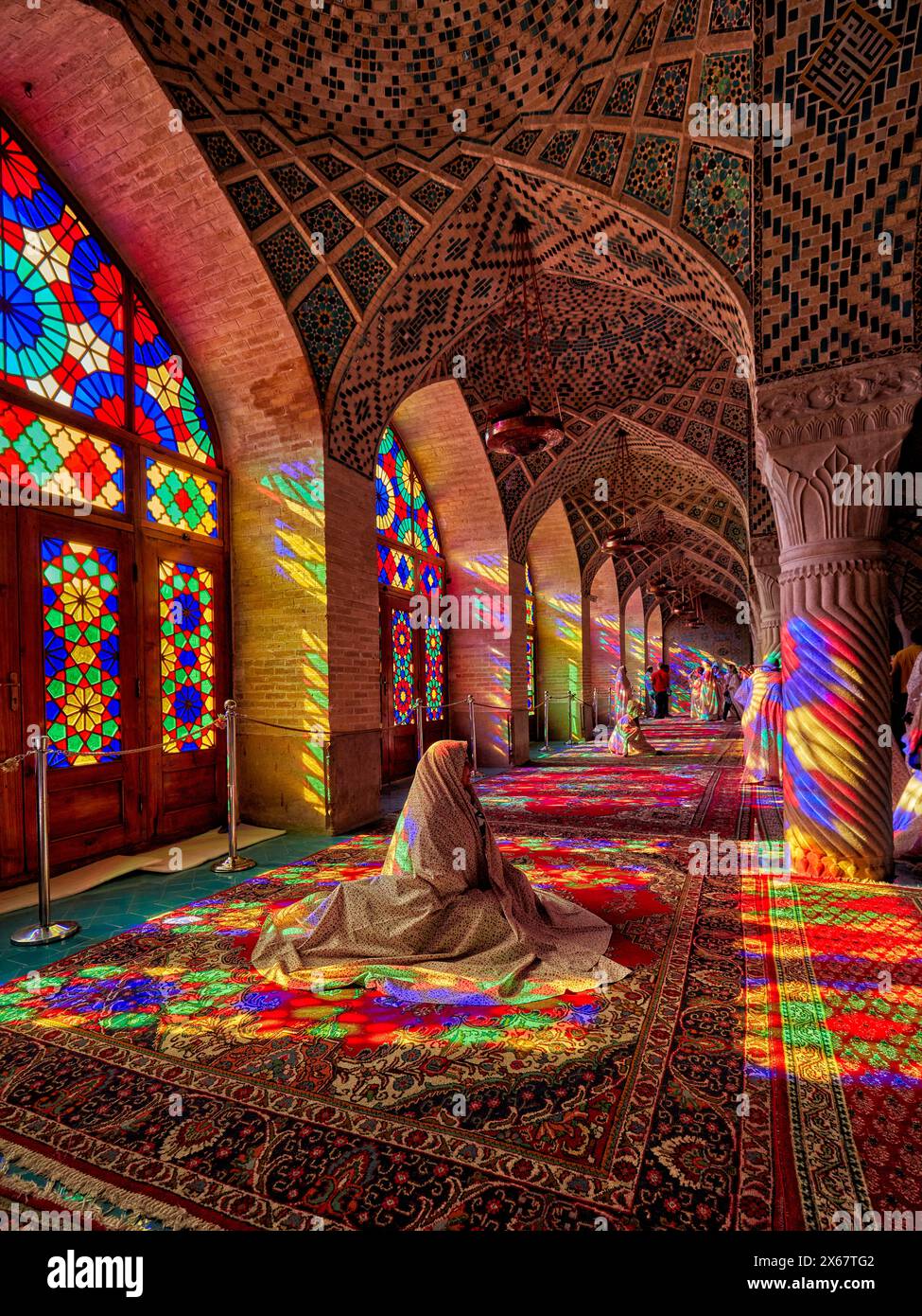 A woman sits in the light from multi-colored stained-glass windows ...