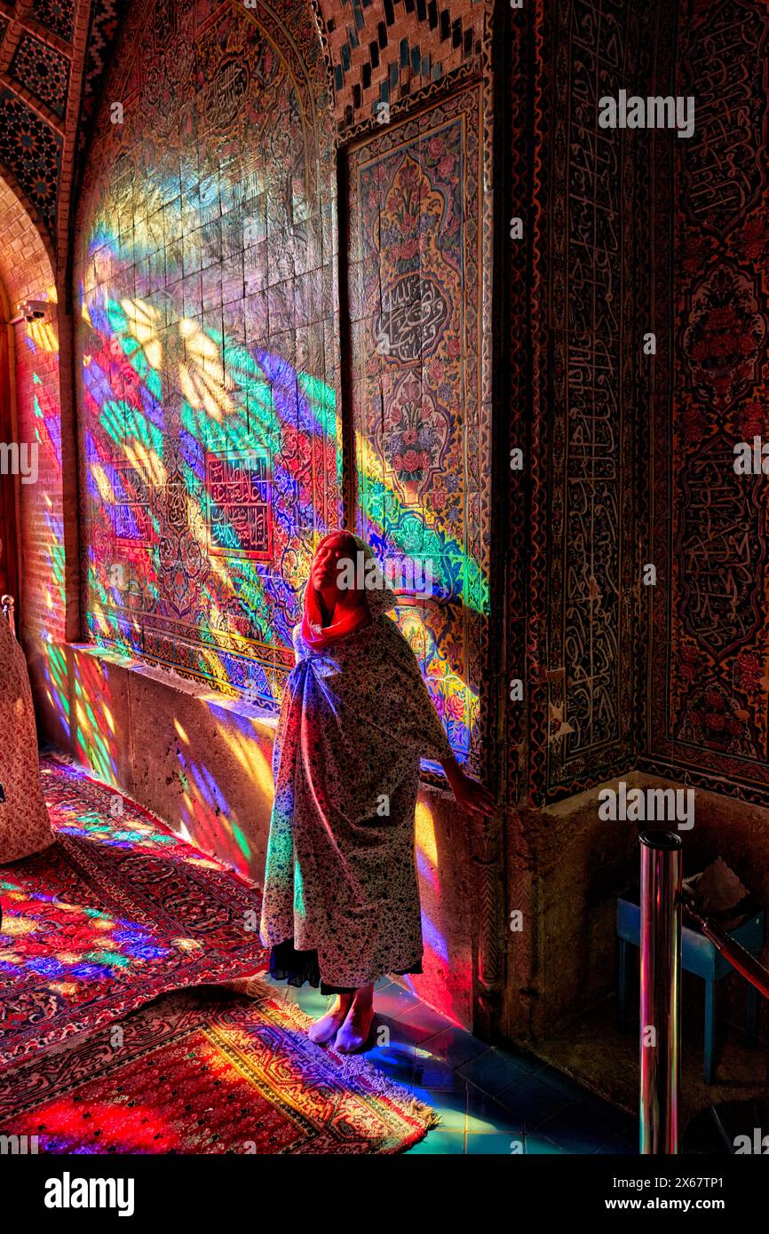A woman stands in the light from multi-colored stained-glass windows ...