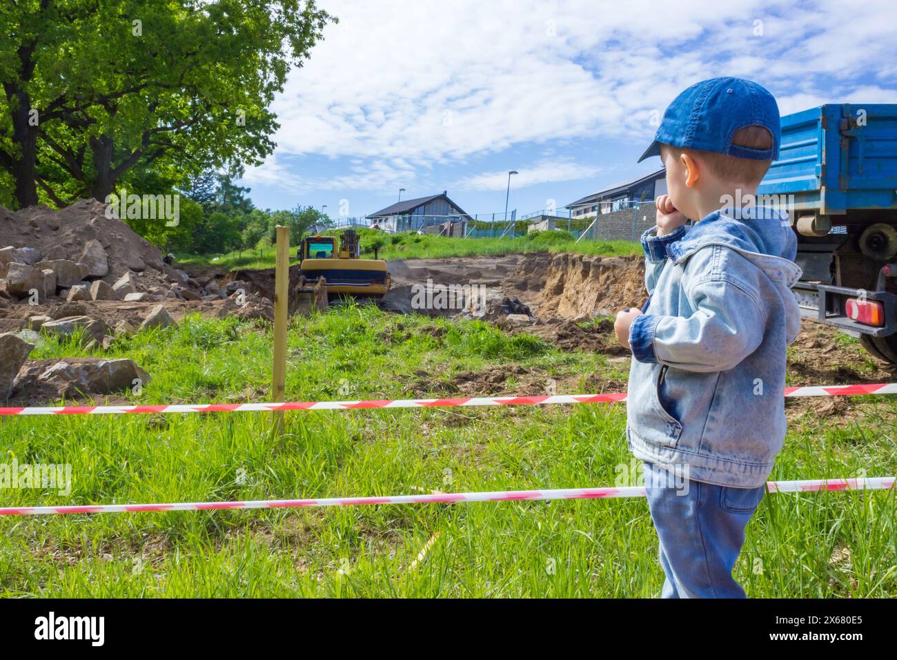 Boy looks at the construction of, clearing rocks with a skid steer ...