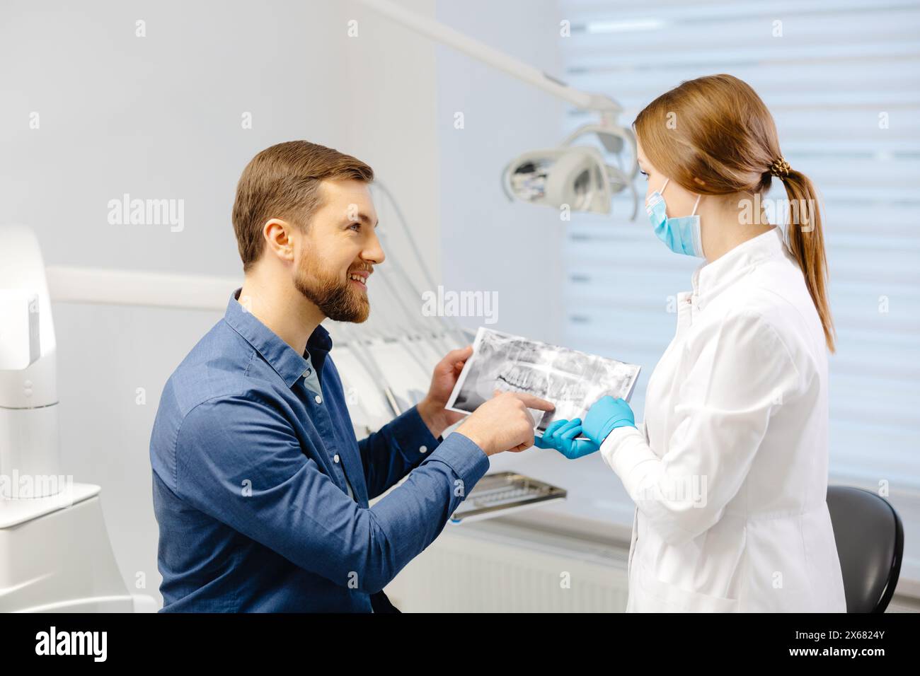 Young attractive man visiting dentist, sitting in dental chair at ...