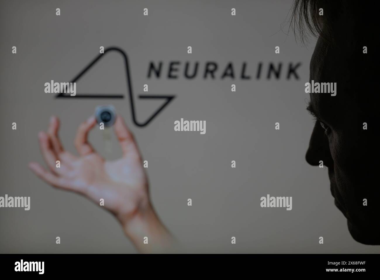 A person is watching a Neuralink chip with Neuralink logo visible in ...