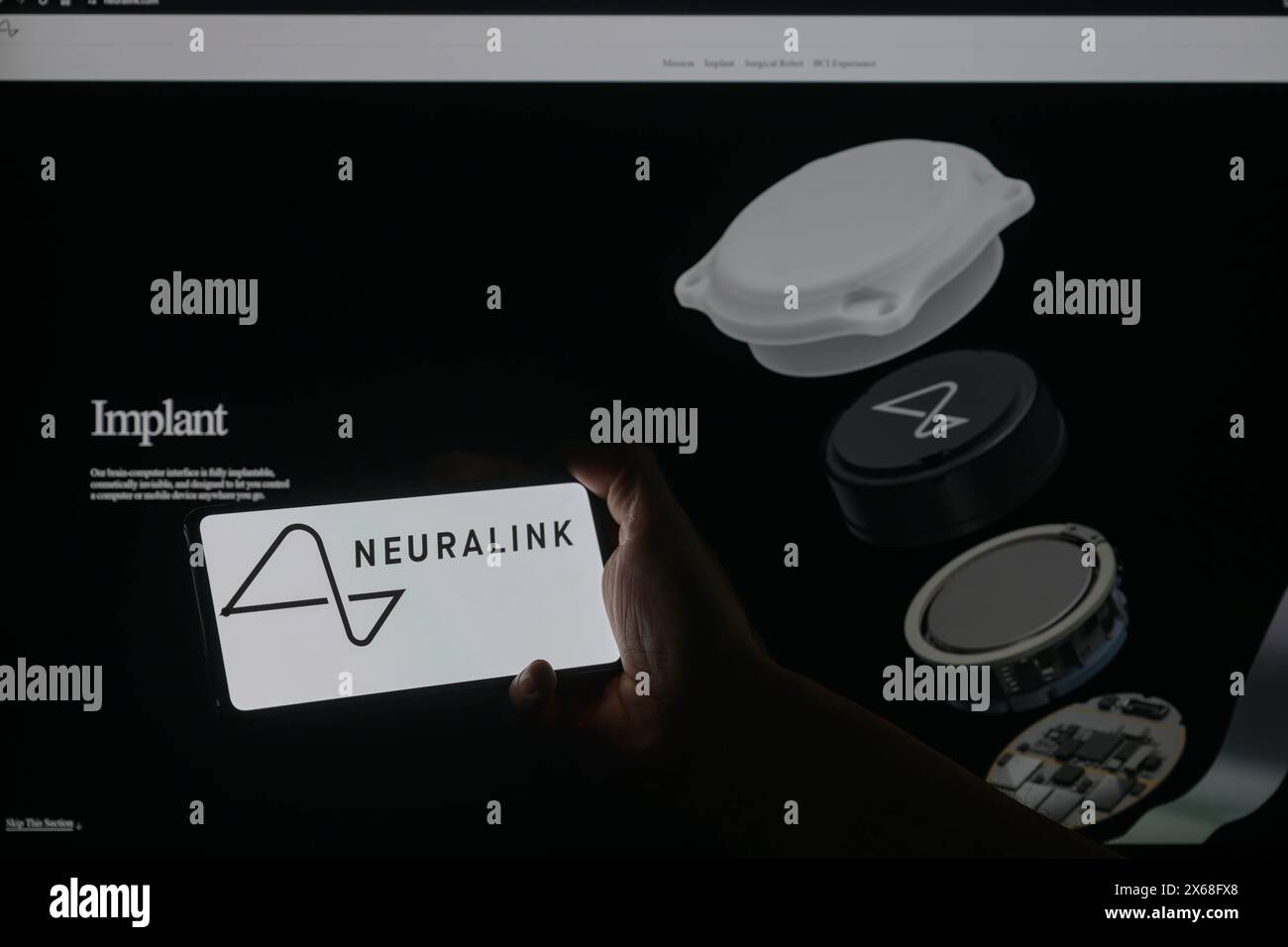 The Neuralink logo is displayed on a smartphone with Neuralink web page ...