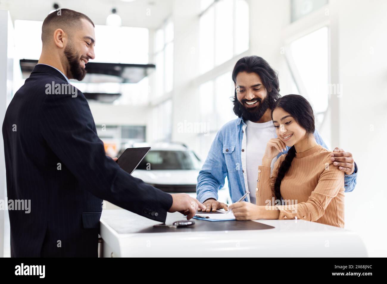 Smiling Couple Signing Documents for New Car at Dealership Showroom ...