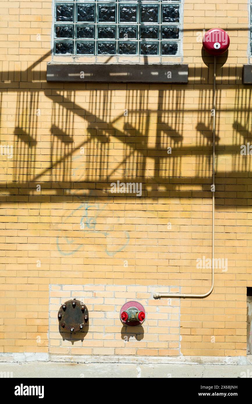 A red fire hydrant is on the side of a building. The shadow of the fire ...