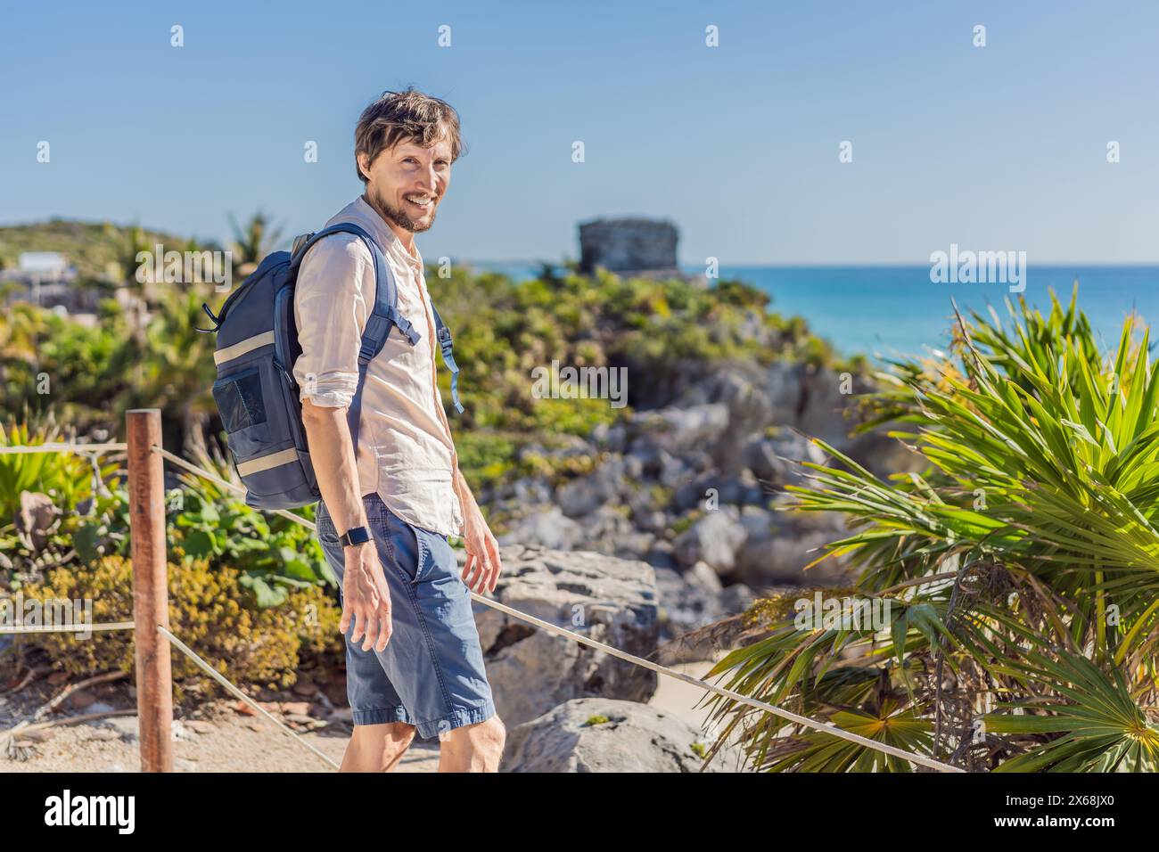 Man tourist enjoying the view Pre-Columbian Mayan walled city of Tulum ...