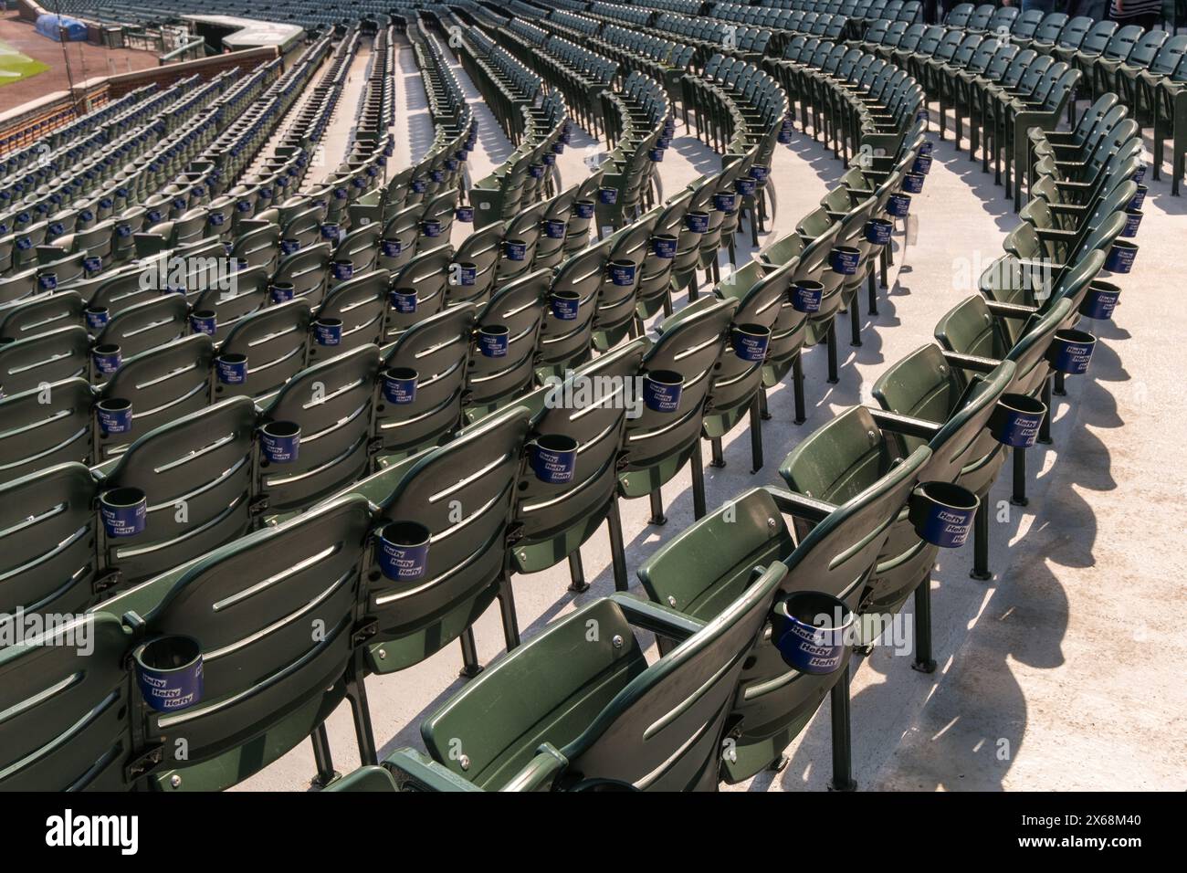 A stadium full of empty seats with blue cups on them. The cups are ...