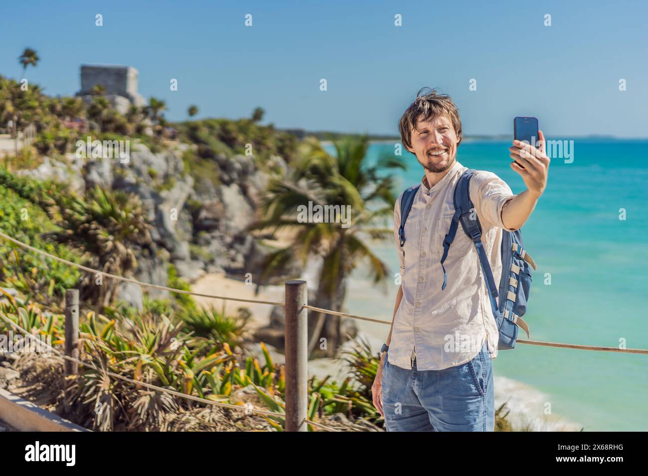 Man tourist enjoying the view Pre-Columbian Mayan walled city of Tulum ...