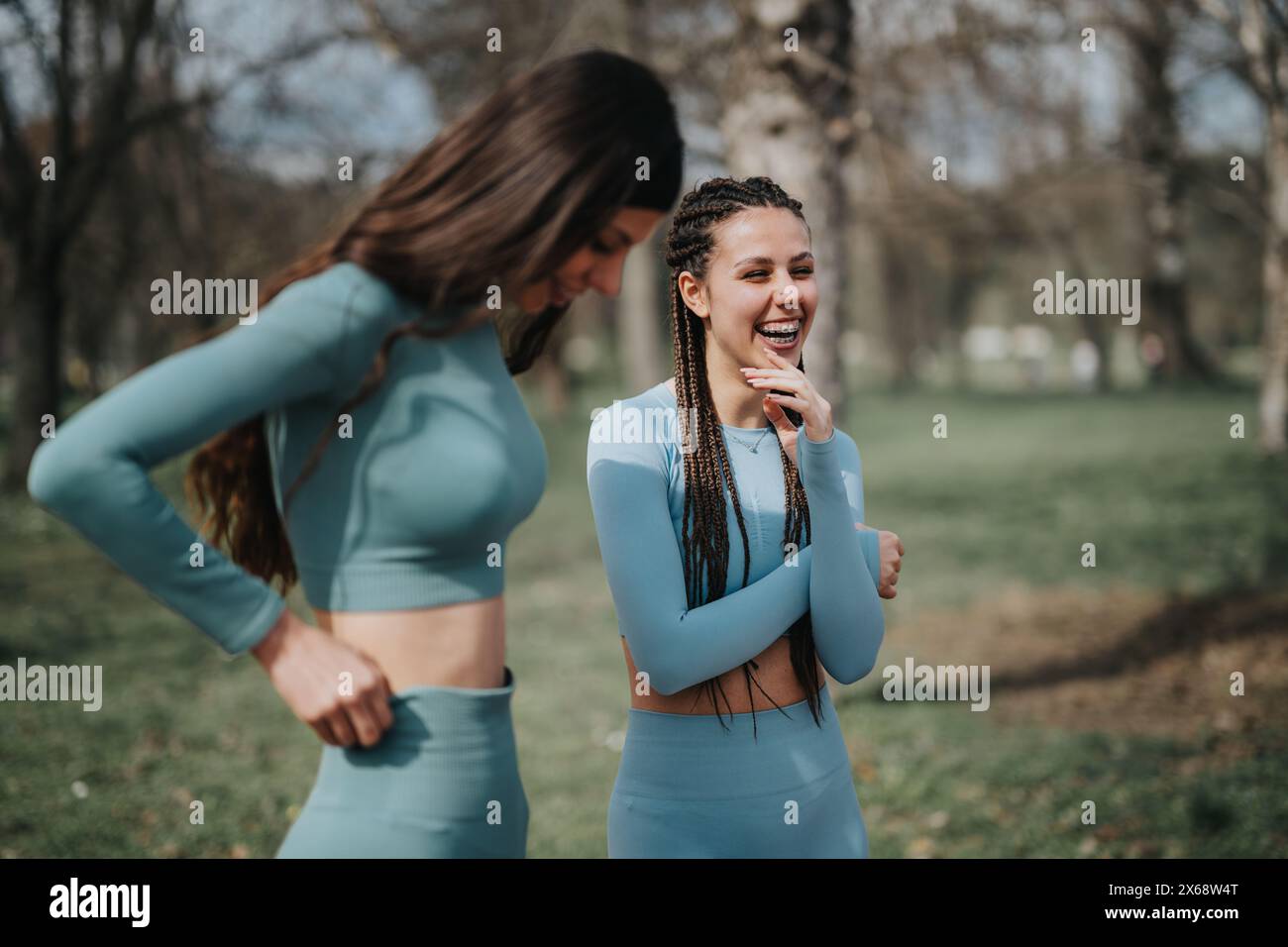 Two young women in workout gear enjoying a laugh together outdoors ...