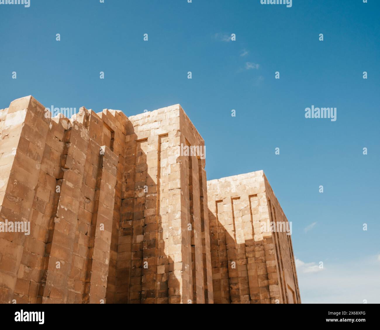 Impressive ancient stone structure against a blue sky in Saqqara, Egypt ...