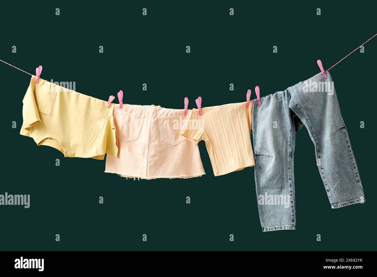 Different clean clothes hanging on rope against green background Stock ...