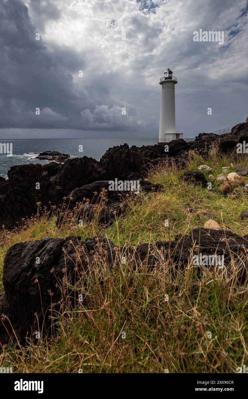 White lighthouse on a steep coast. Dramatic clouds with a view of the ...
