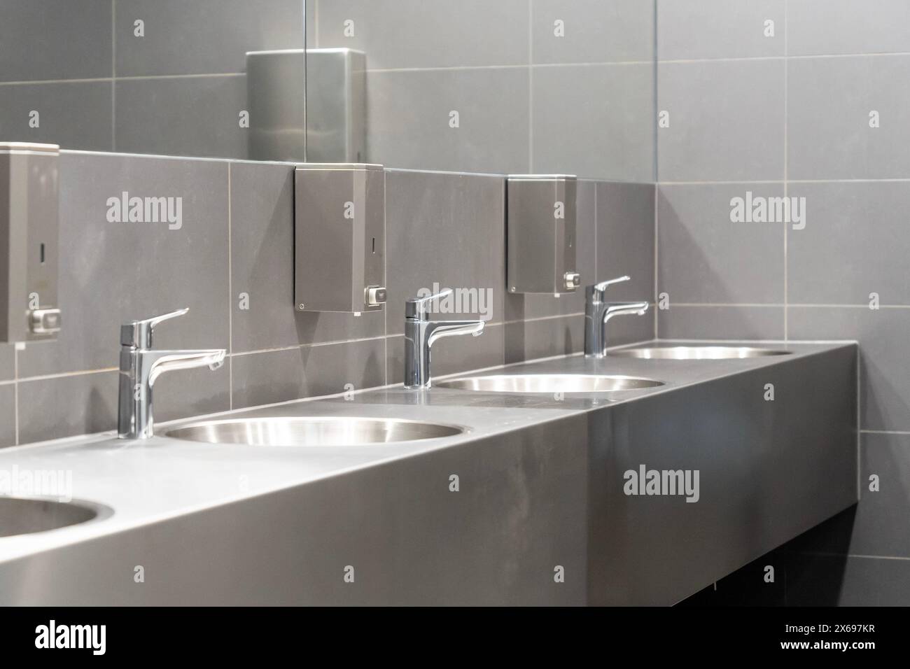 A row of metallic toilets in a gray tiled public toilet Stock Photo - Alamy