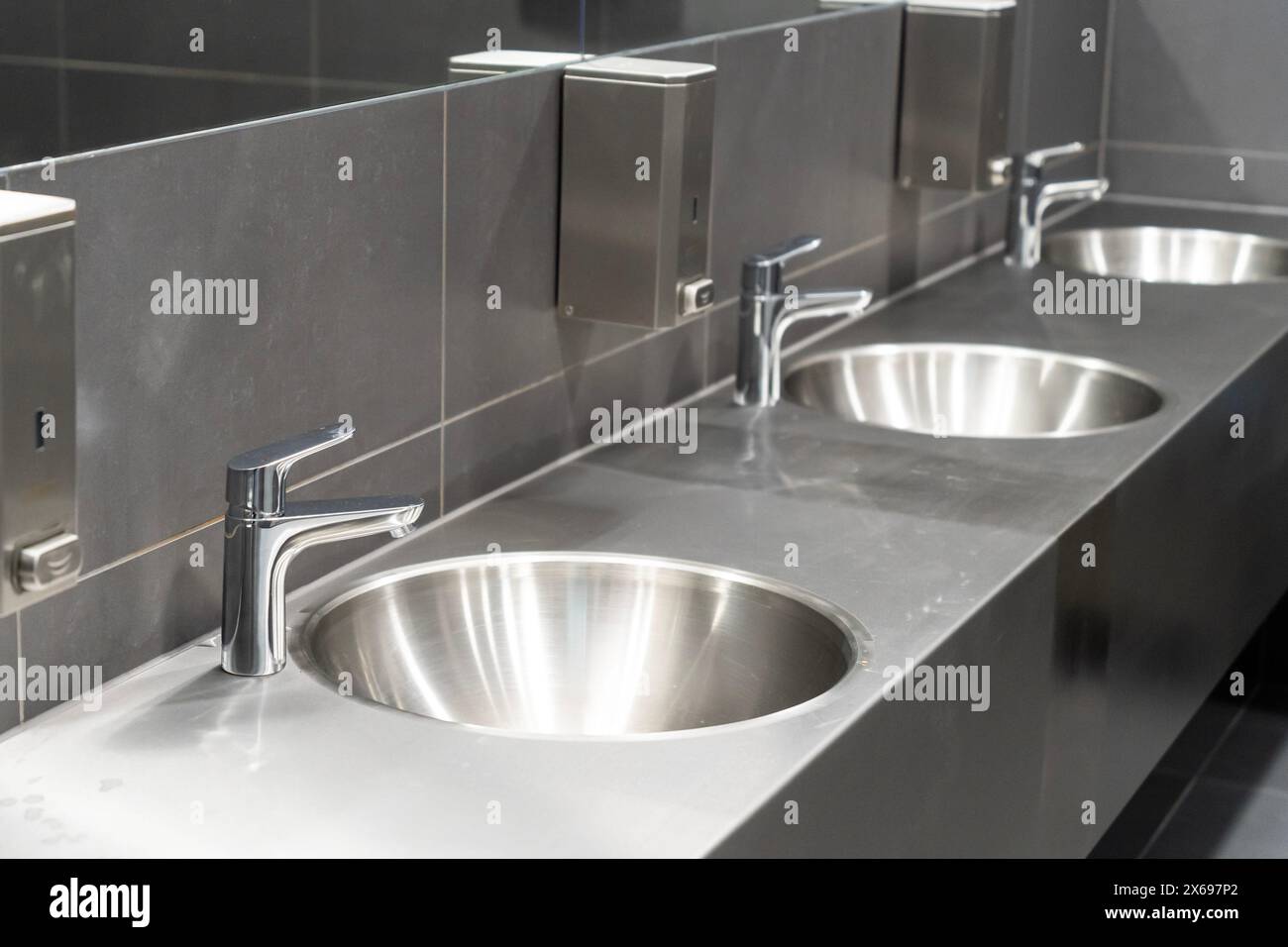 A row of metallic toilets in a gray tiled public toilet Stock Photo - Alamy