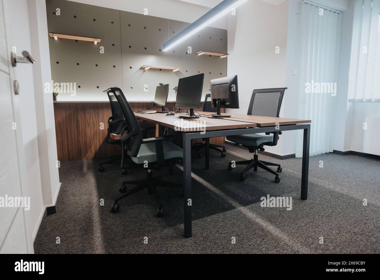 Modern office with natural wood desks and ergonomic chairs under ...