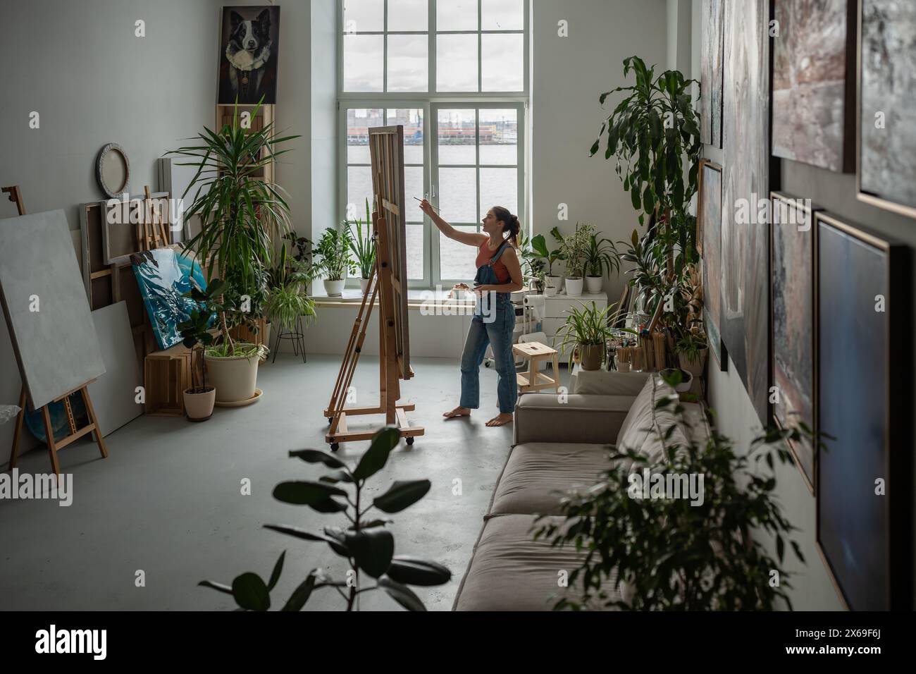 Serious woman painter in art studio creating masterpiece on large canvas. Artistic creative work ...