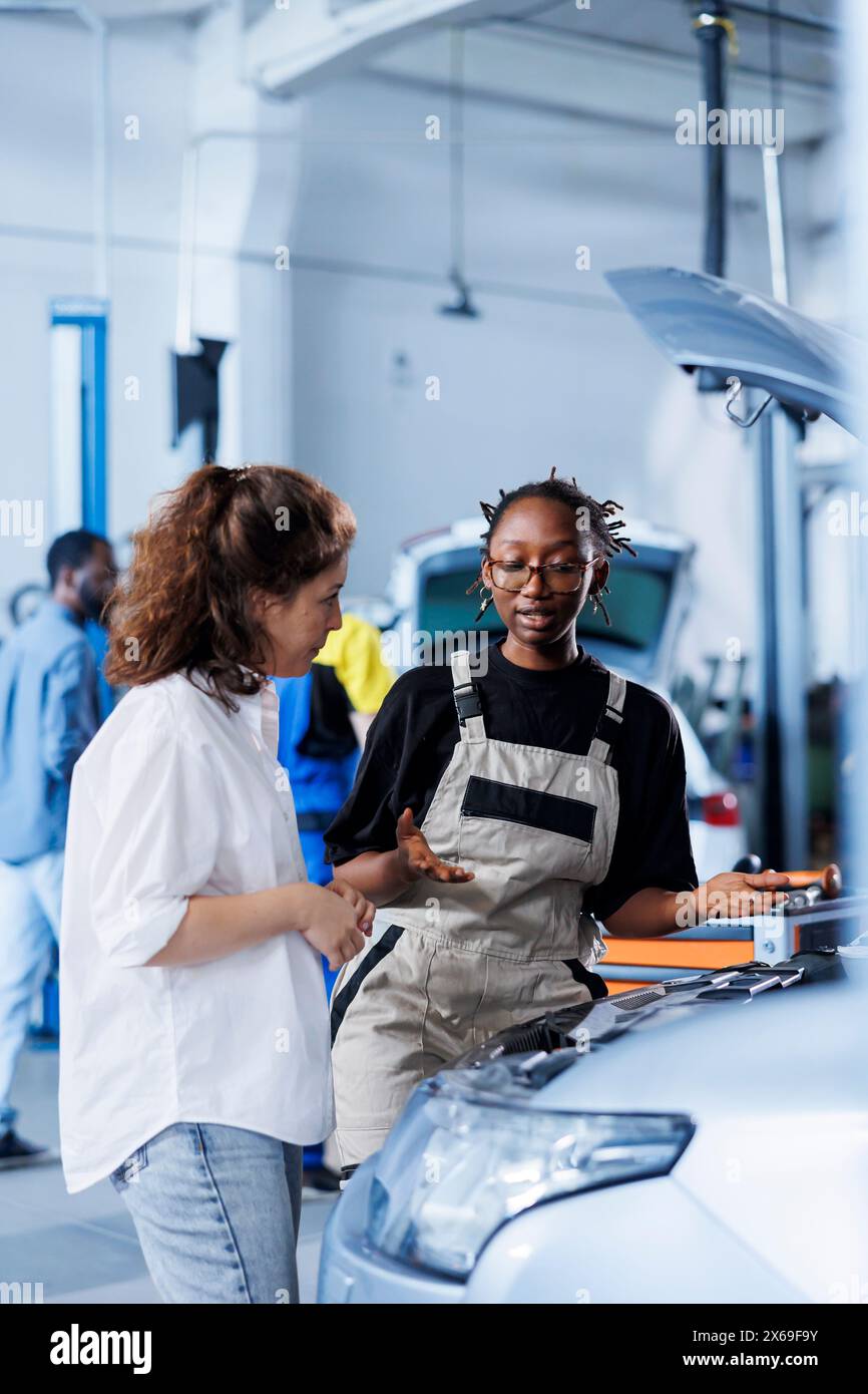 Trained mechanic helping client with car maintenance in auto repair ...