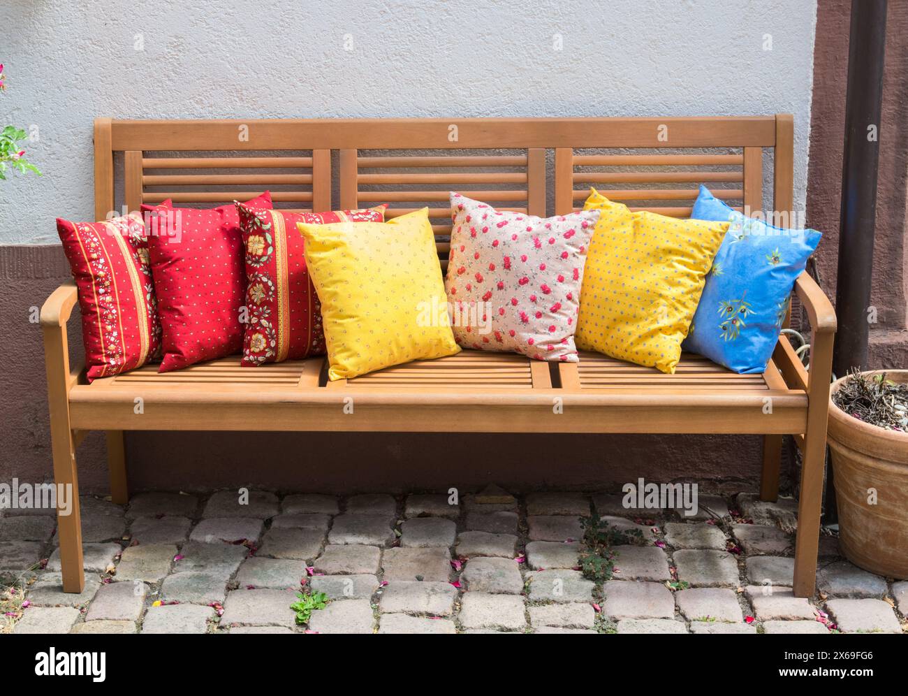 Wood romantic bench with a lot of multicolor pillows outdoor near stone ...