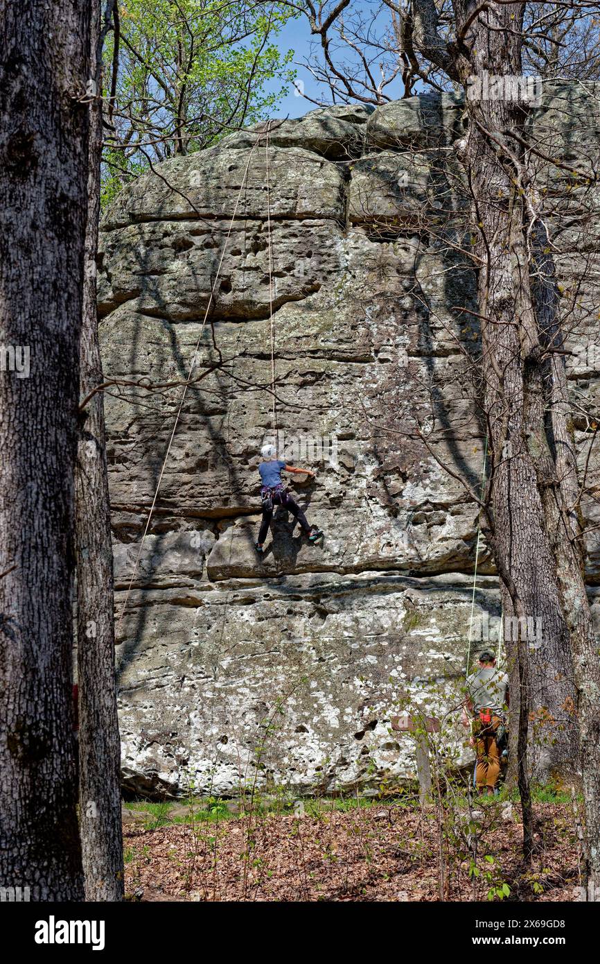 Woman climber ascending upwards on a rope attached on the top carefully ...