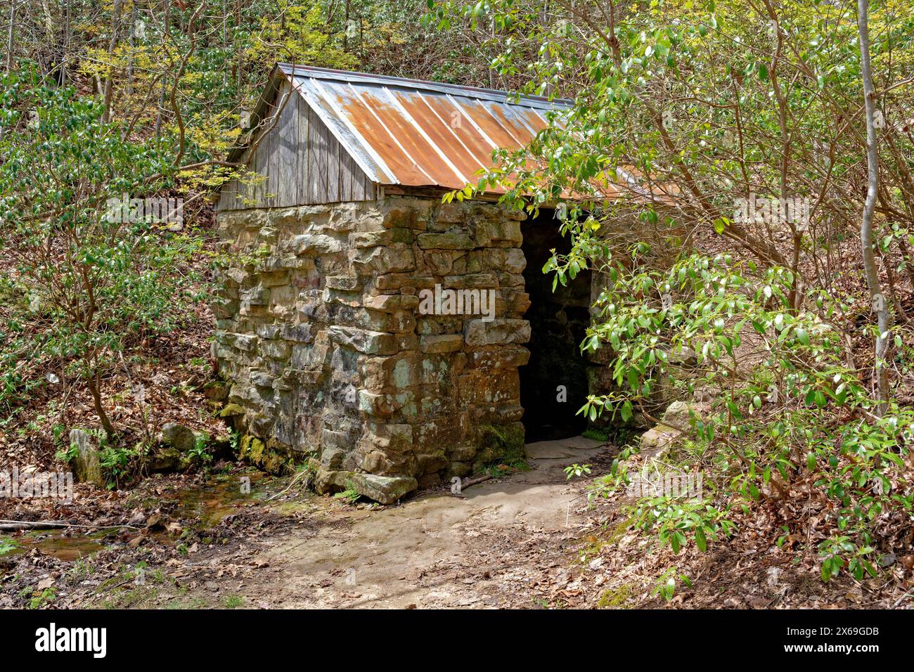 A creek flowing through the old stone spring house with metal roof ...