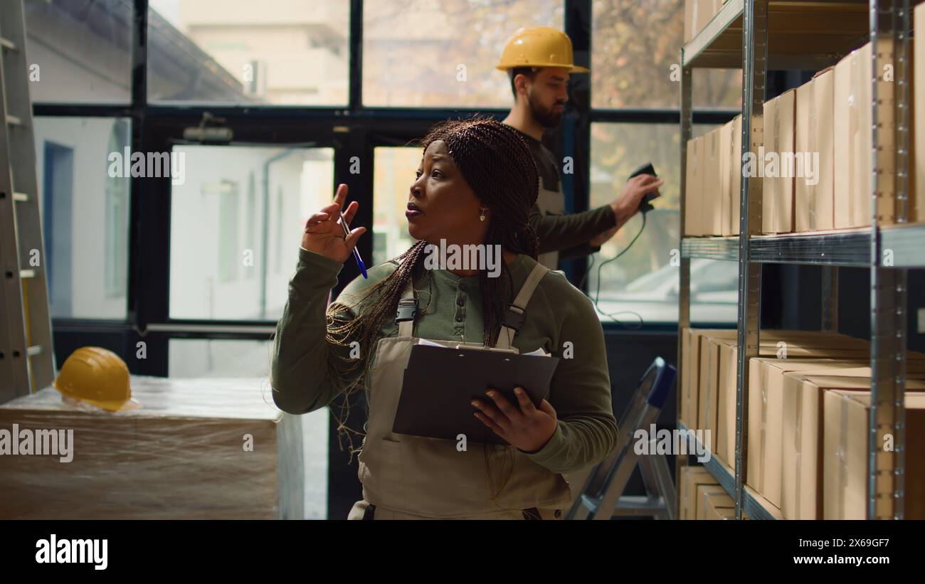 Dolly out tracking shot of african american woman in warehouse inputing ...