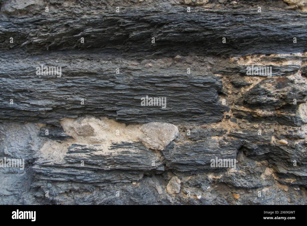 Gray structural stone wall of the ancient building consists of old dark ...