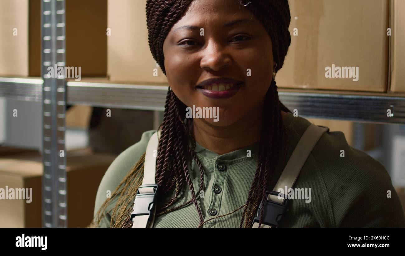 Portrait of cheerful african american warehouse supervisor inputing ...