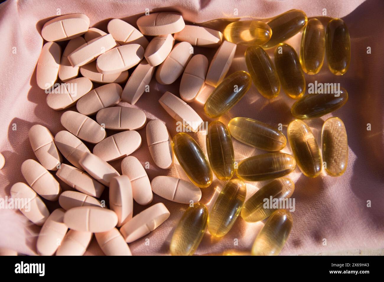 Vitamins and omega 3 fish oil on the natural wood background with pink ...