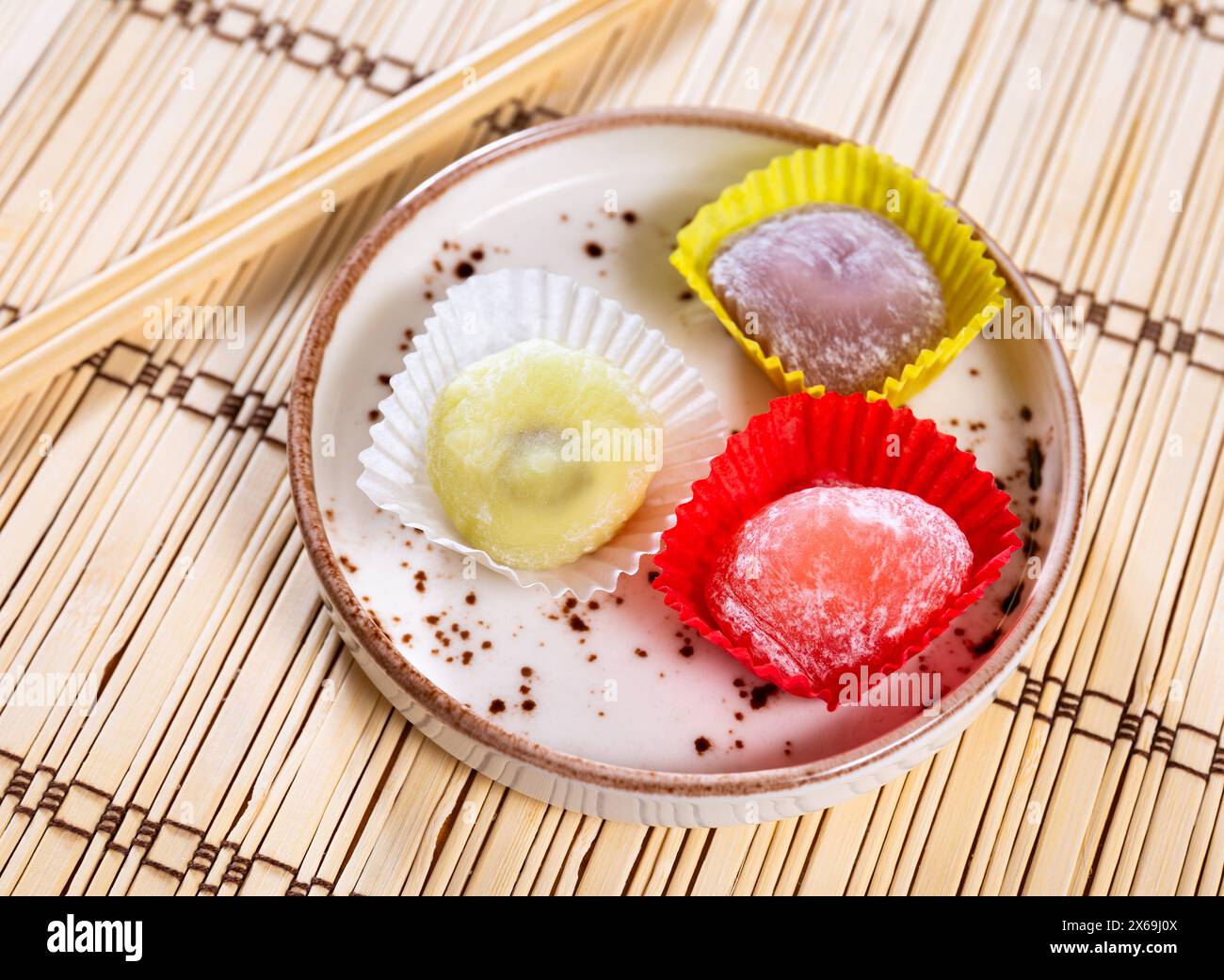 Colorful mochi desserts in paper liners on plate over bamboo mat Stock ...